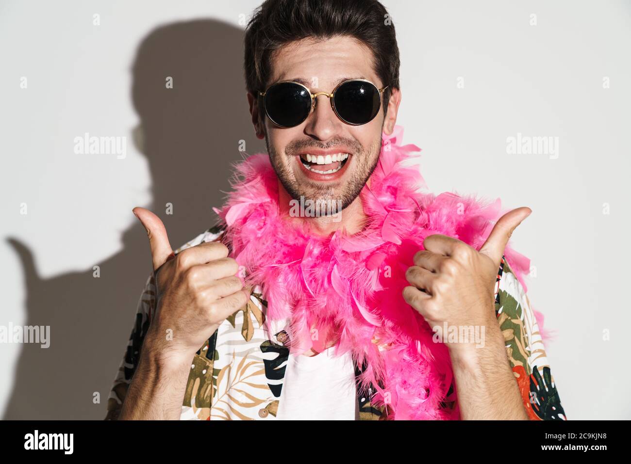 Portrait of handsome excited man wearing boa showing thumbs up isolated ...