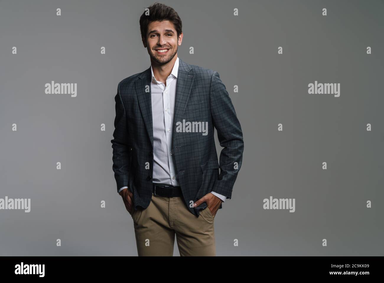 Photo of pleased businessman in jacket posing and smiling at camera ...