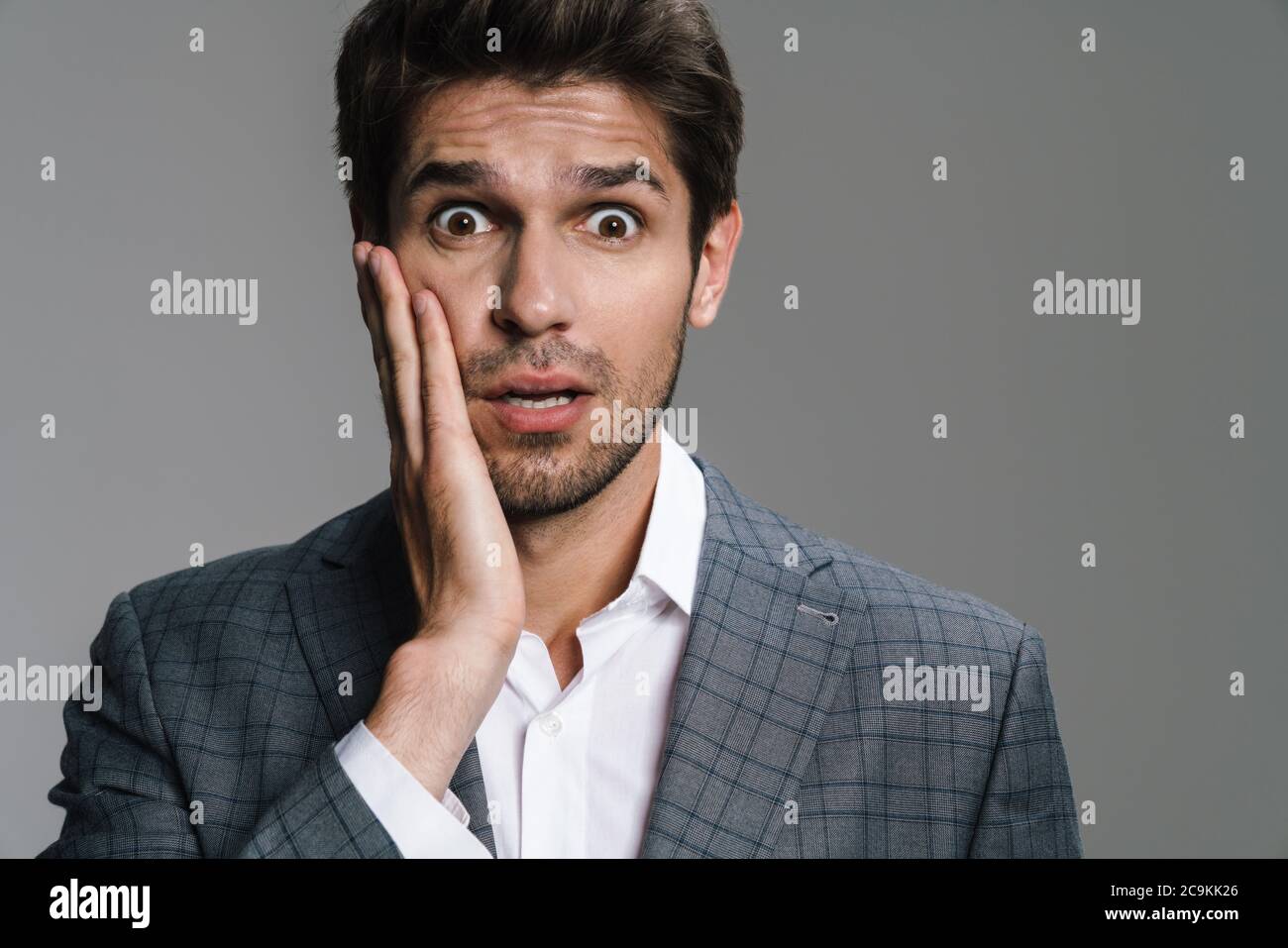 Photo Of Unshaven Shocked Businessman In Jacket Expressing Surprise On