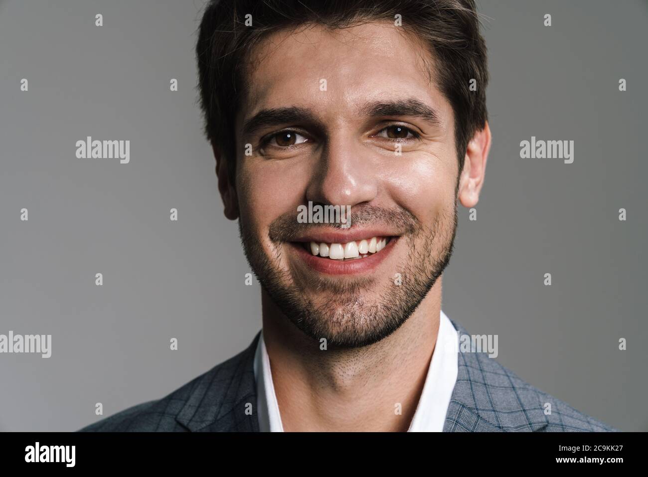 Photo of pleased businessman in jacket posing and smiling at camera ...