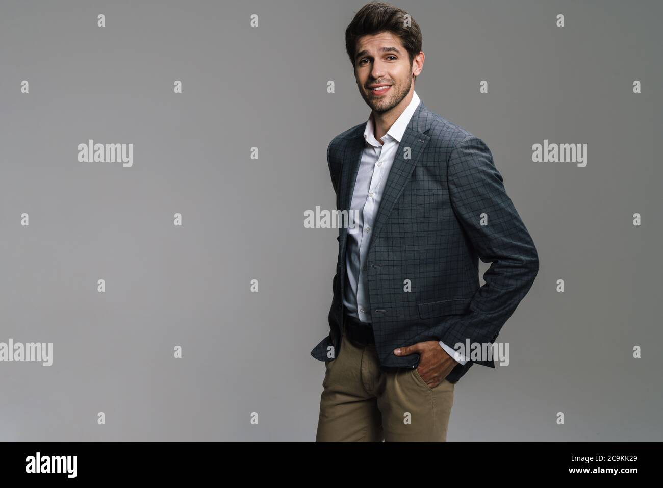 Photo of pleased businessman in jacket posing and smiling at camera ...