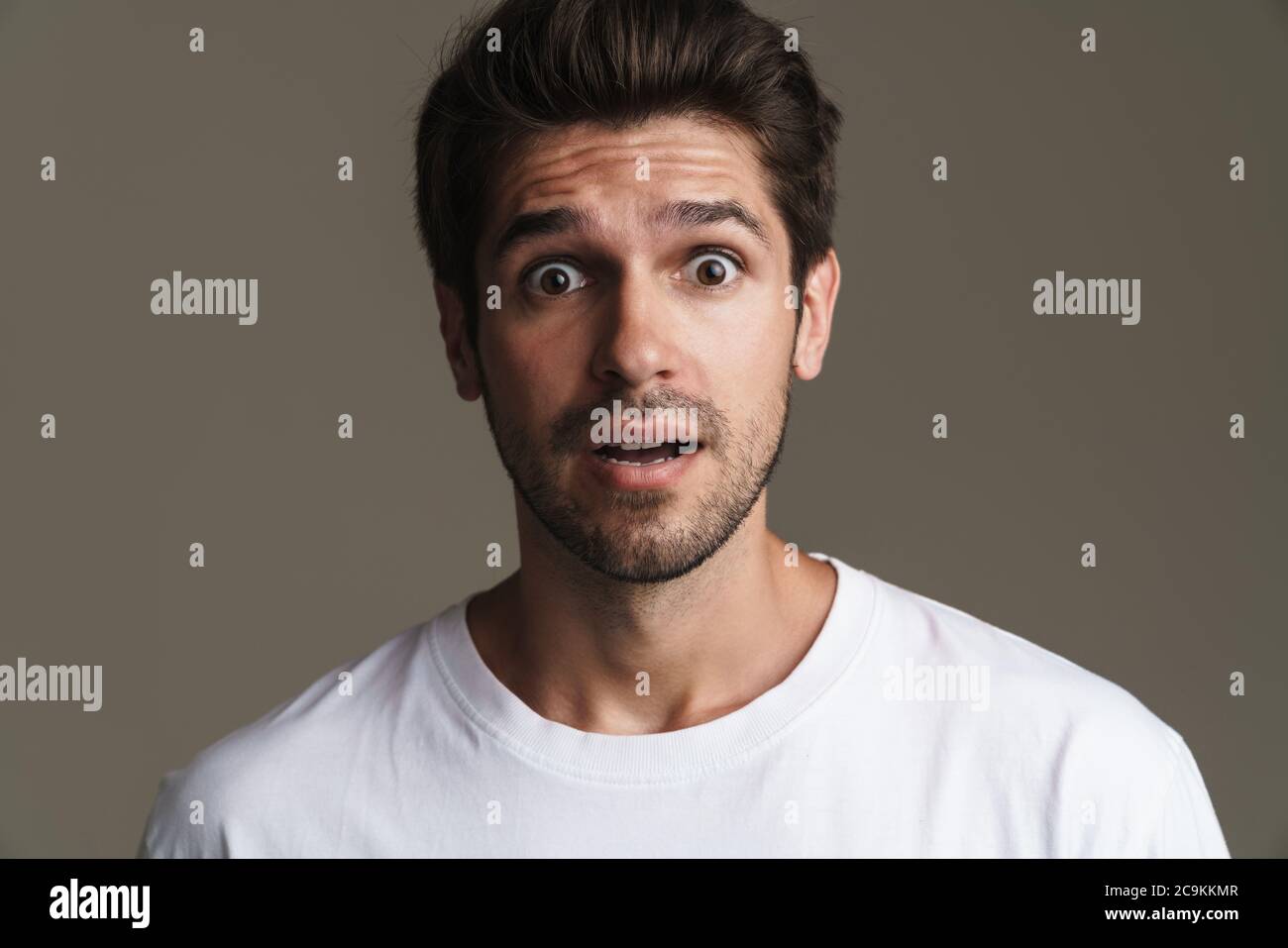 Portrait of shocked young man in basic t-shirt expressing surprise on ...