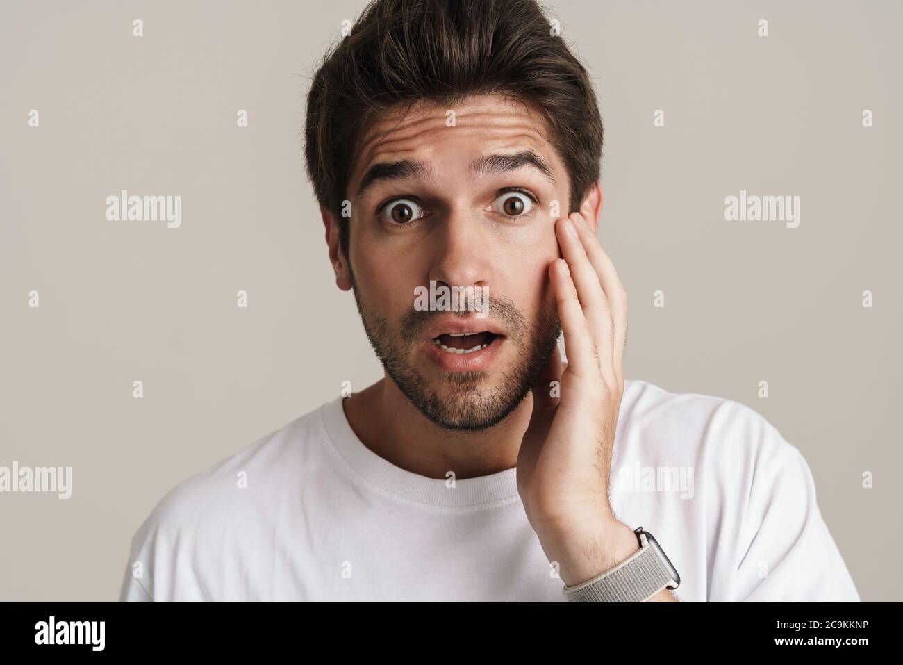 Portrait of shocked young man in basic t-shirt expressing surprise on ...