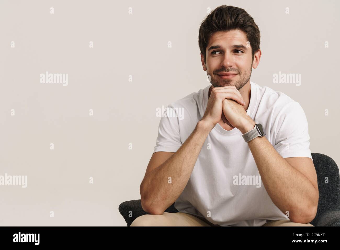 Portrait of unshaven smiling man looking aside while sitting on ...