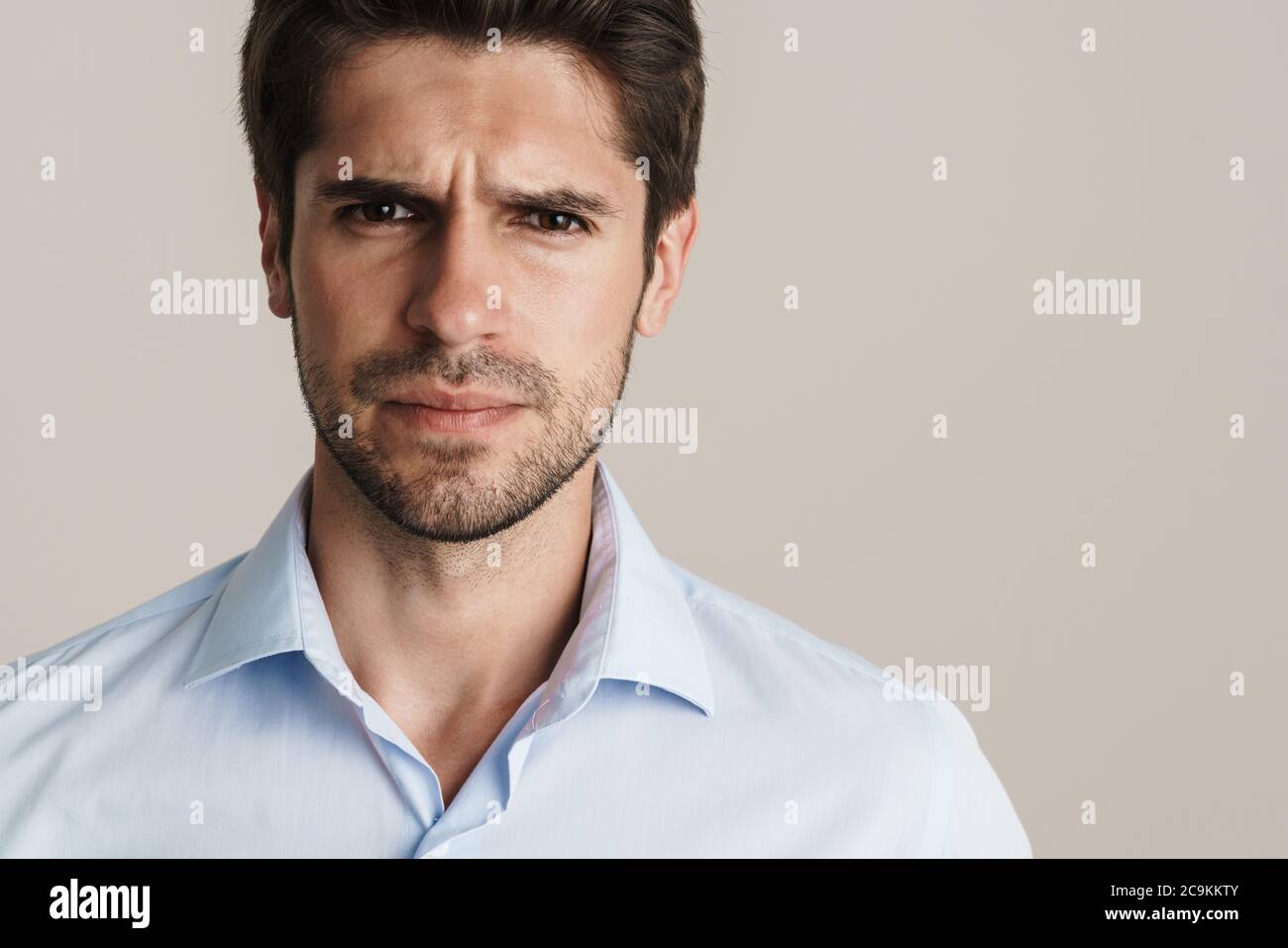 Portrait of unshaven displeased man posing and looking at camera ...