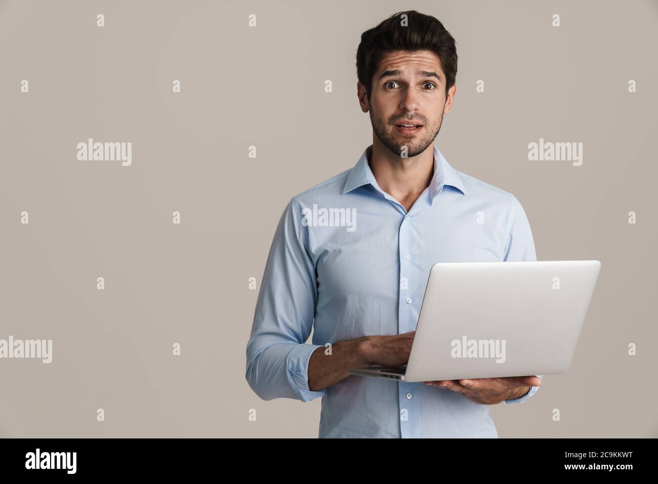 Portrait of shocked handsome man looking at camera while using computer ...