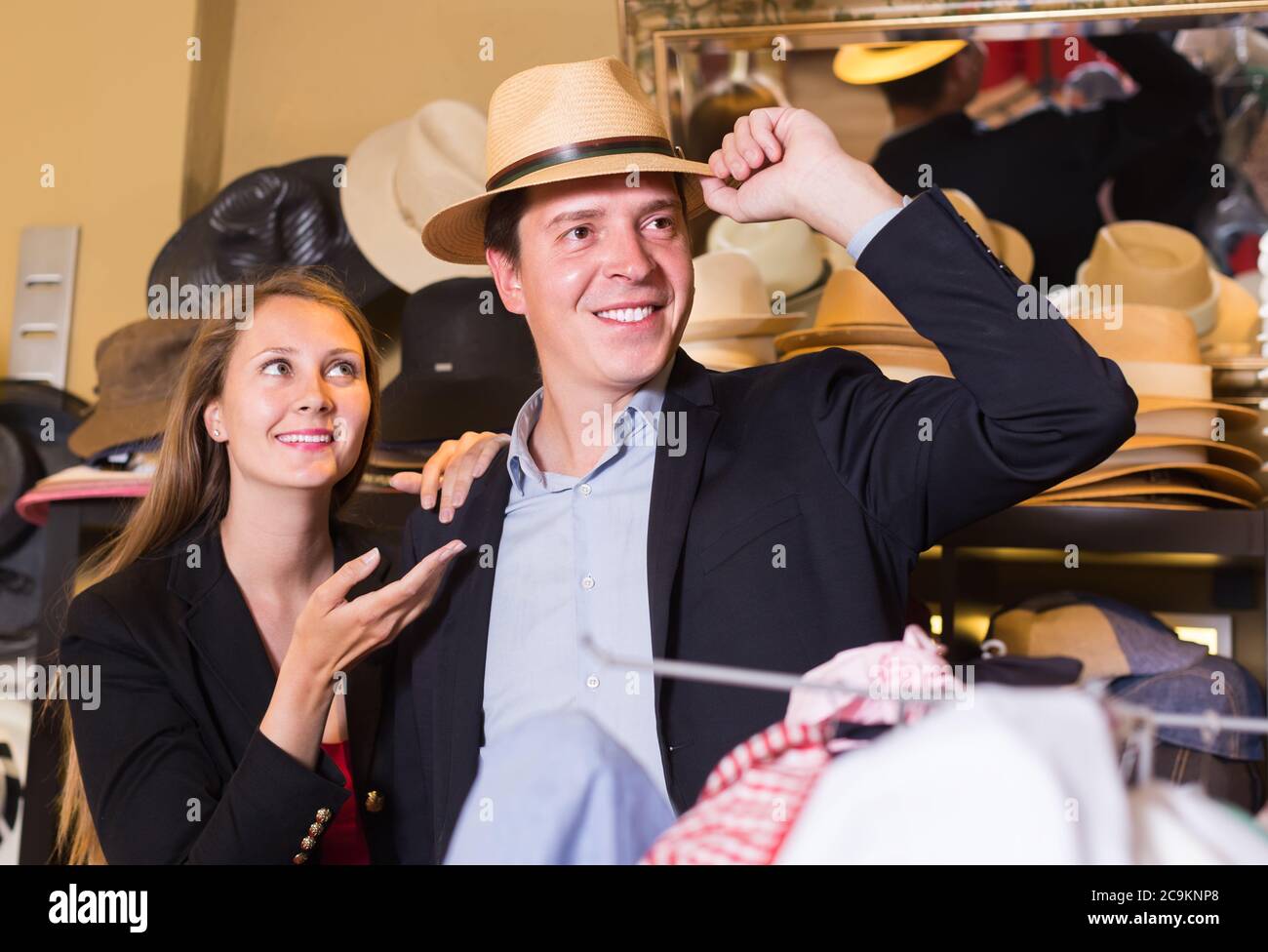 happy female and man choosing hats from the assortment in the store ...