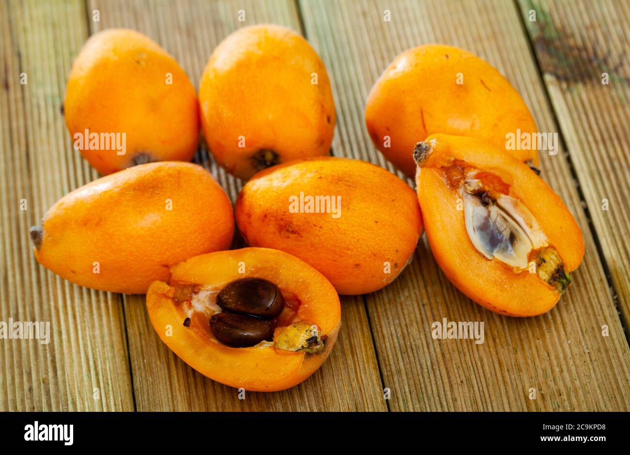 Whole and halved fresh loquat fruit or chinese plum on wooden ...