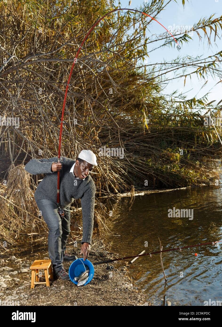 Portrait of afro fisherman standing near river and pulling fish Stock ...