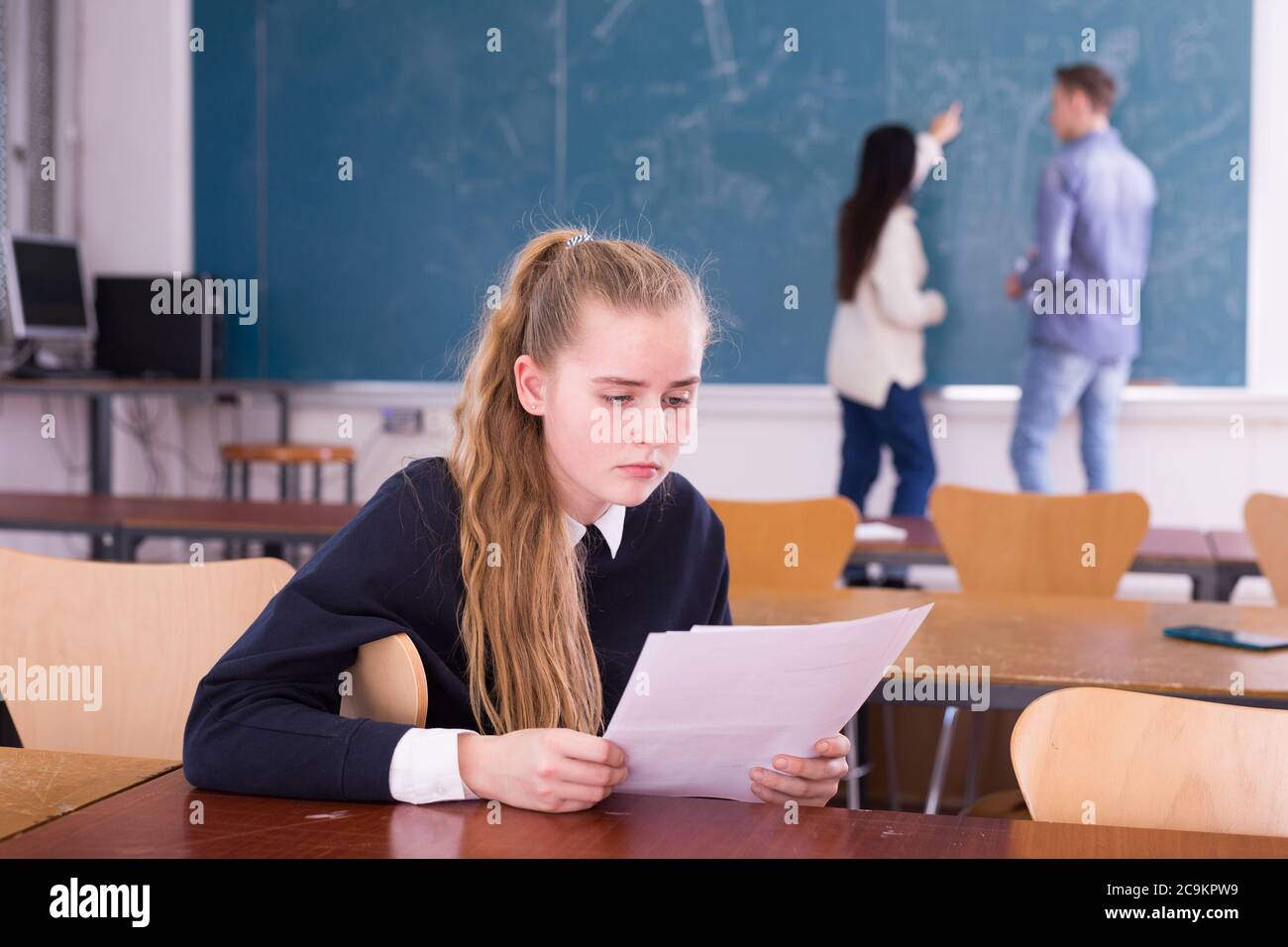 Portrait of frustrated teen girl student sitting in classroom with ...