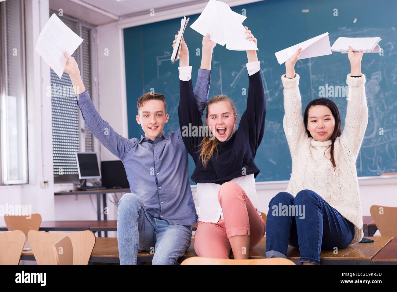 Group of young students expressing happiness while holding papers after ...