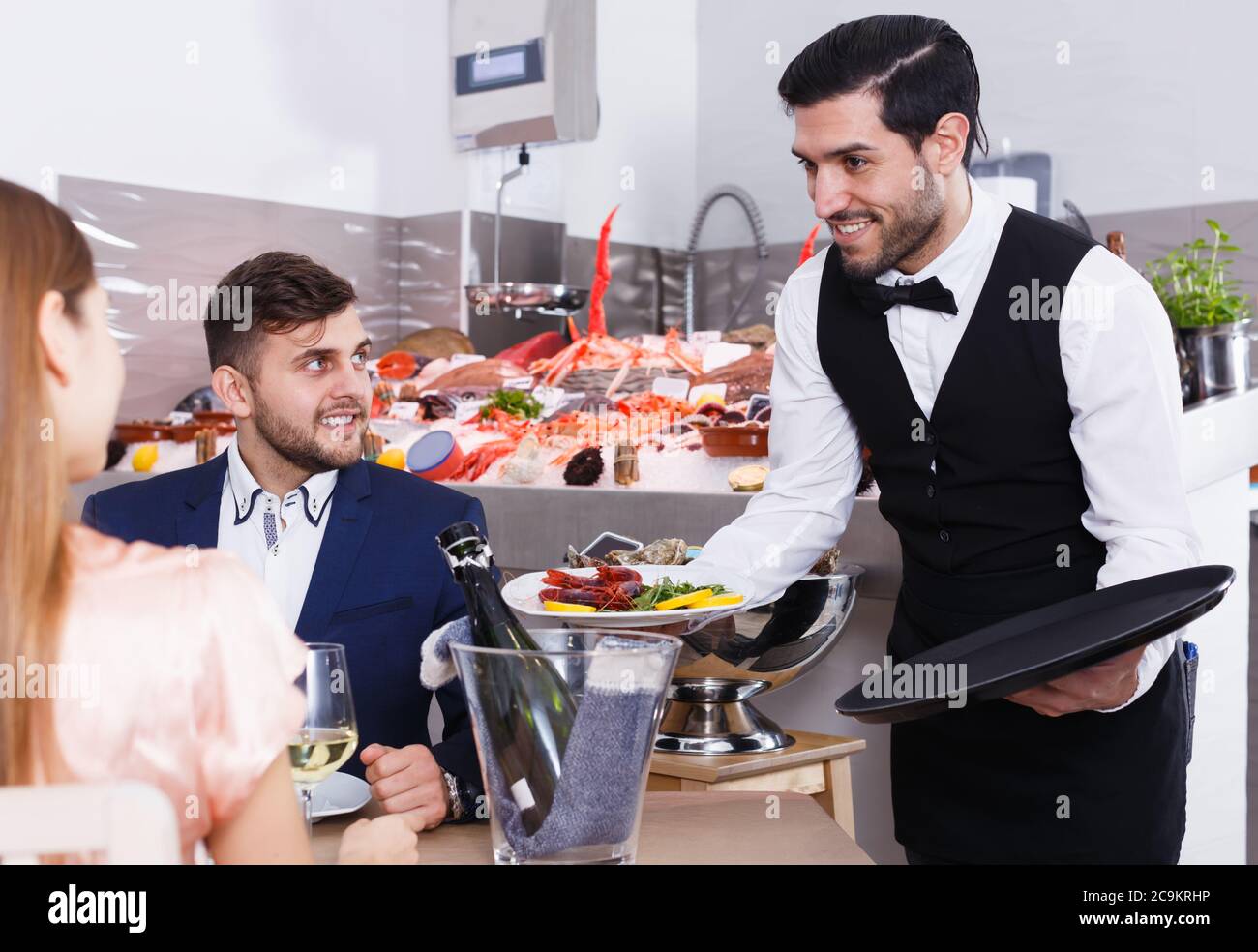 Man waiter serving seafood meals to visitors of fish restaurant Stock ...