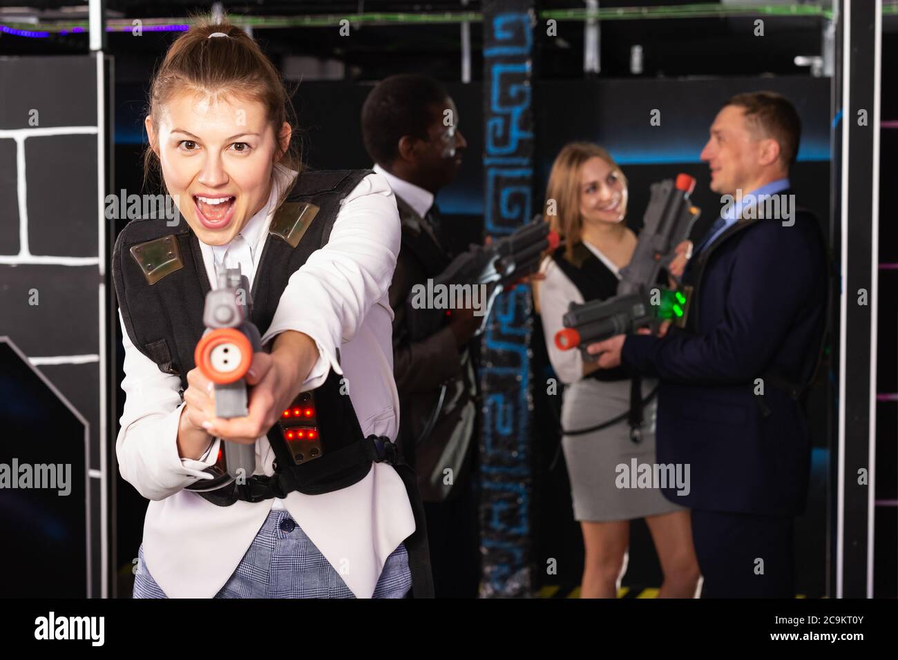 Emotional portrait of female playing laser tag with her co-workers on ...