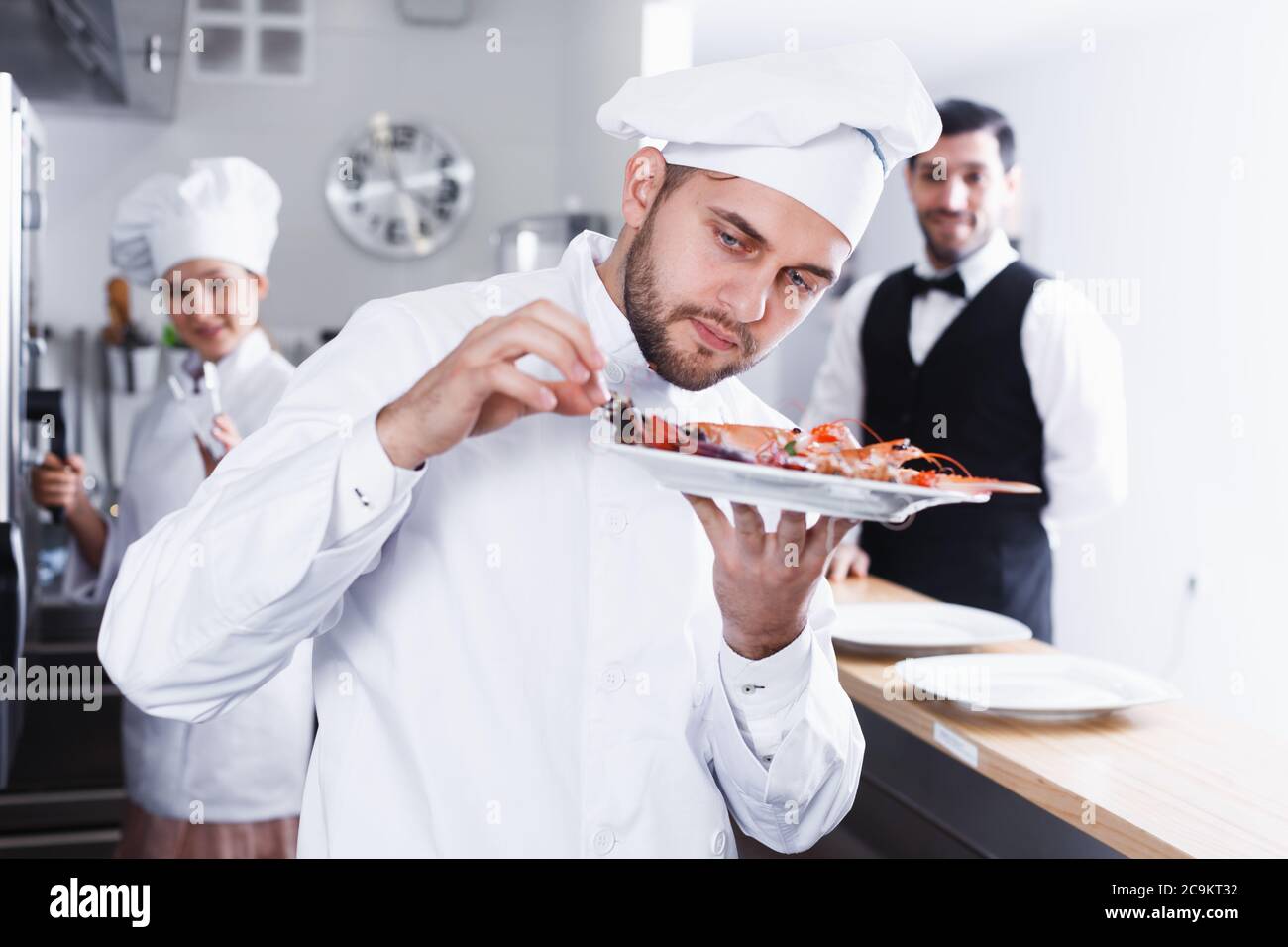Head chef checking dishes in kitchen of fish restaurant before serving ...