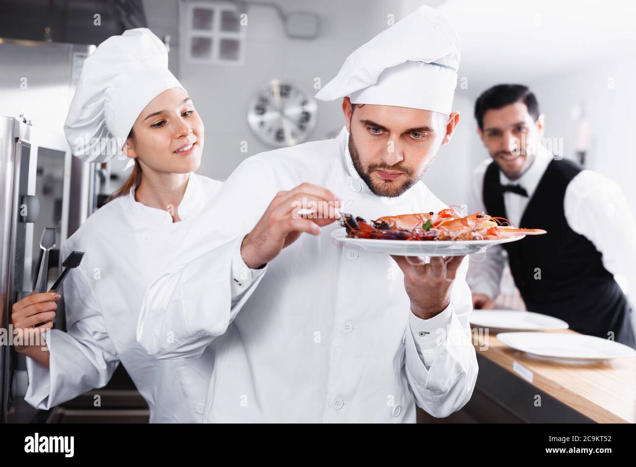 Head glad cheerful positive chef checking dishes in kitchen of fish ...