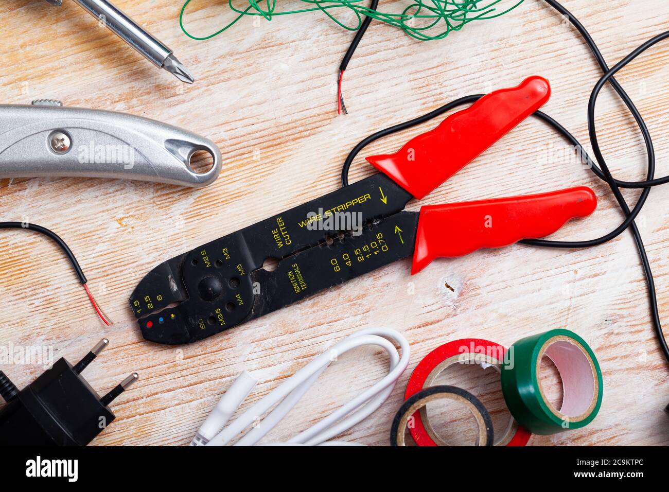 Wire stripper with red plastic handles with wires on wooden surface ...