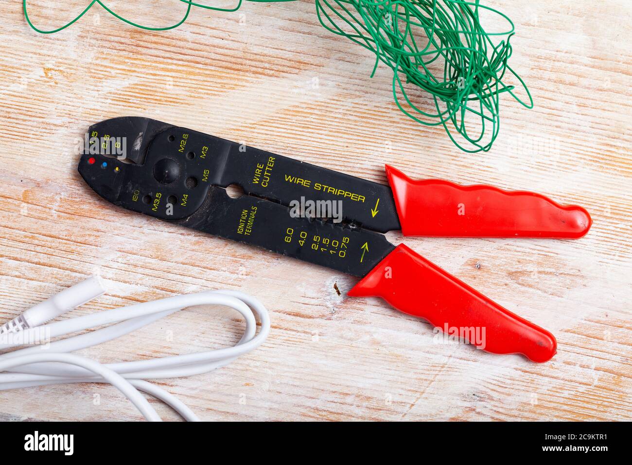 Wire stripper with red plastic handles with wires on wooden surface ...