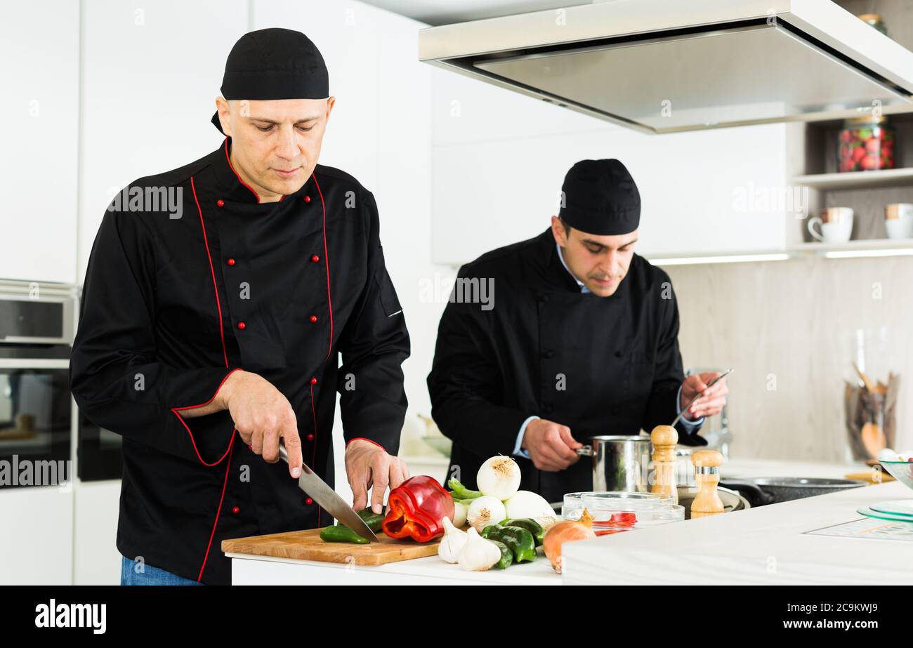 Men kitchener in uniform are cutting vegetables for salad in the ...