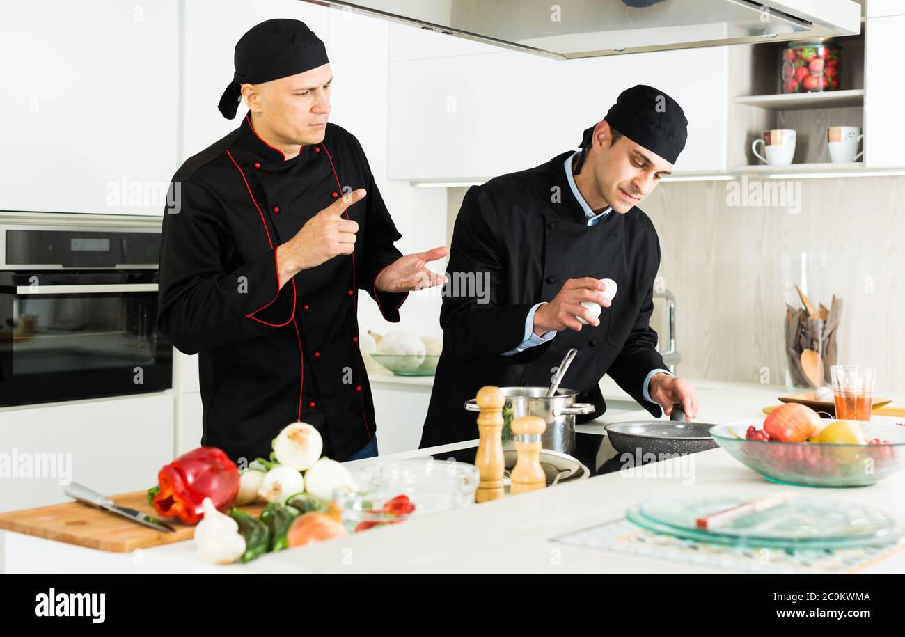 Professional men chefs in black uniform having conflict on kitchen ...