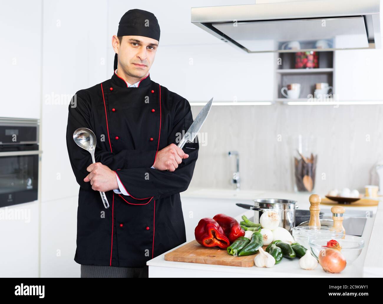 Professional cook in black uniform standing near workplace on kitchen ...