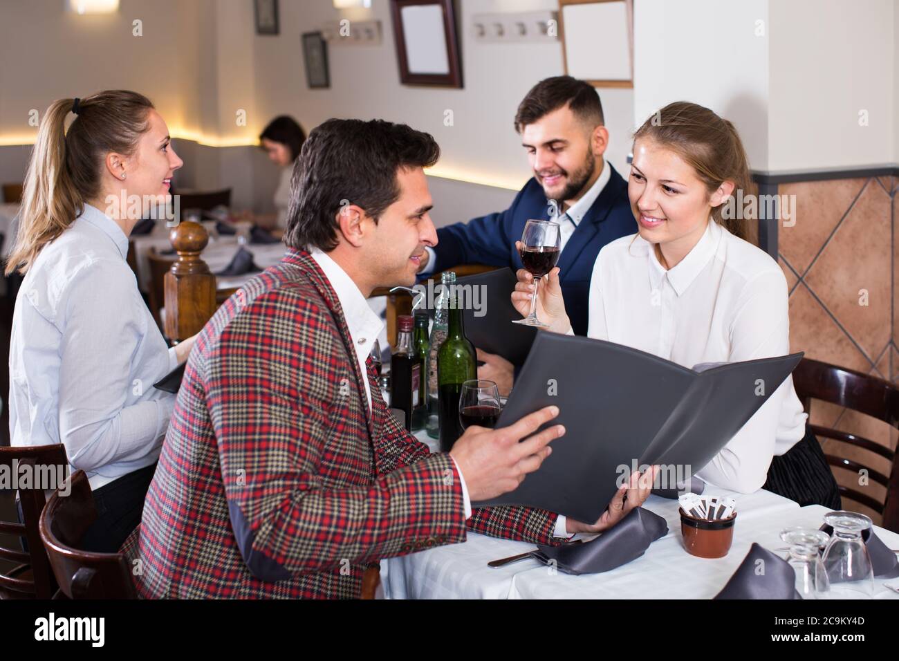 positive people sitting at table in cozy restaurant, discussing menu ...