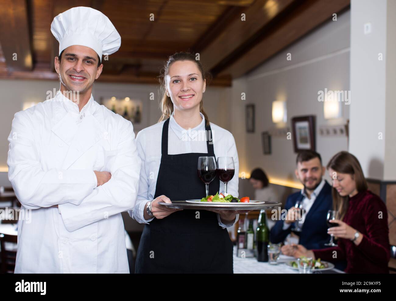 Portrait of confident male chef and smiling waitress in restaurant ...