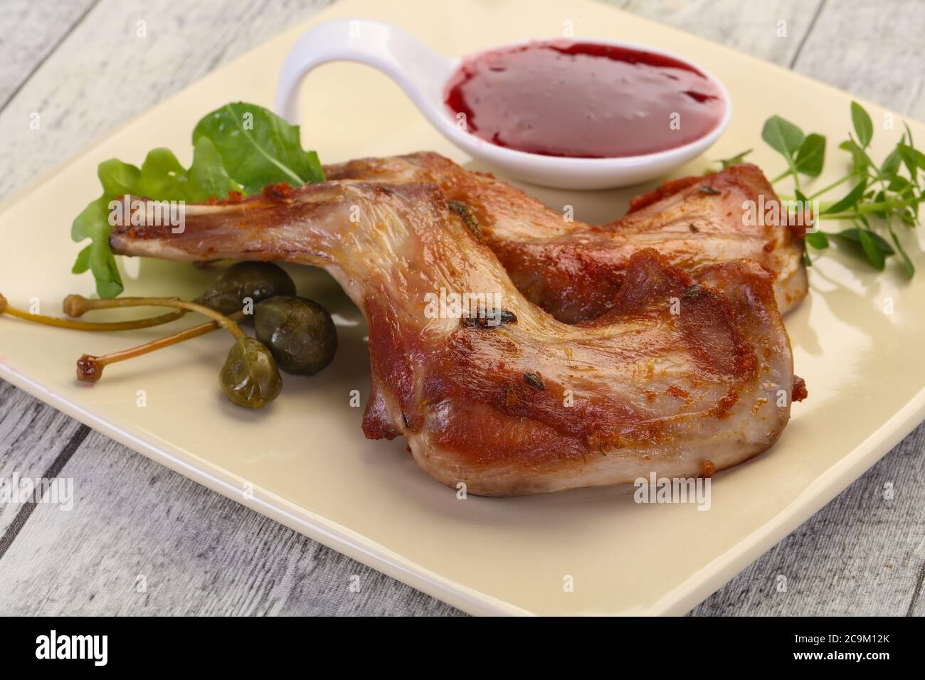 Roasted rabbit legs with cowberry sauce Stock Photo - Alamy