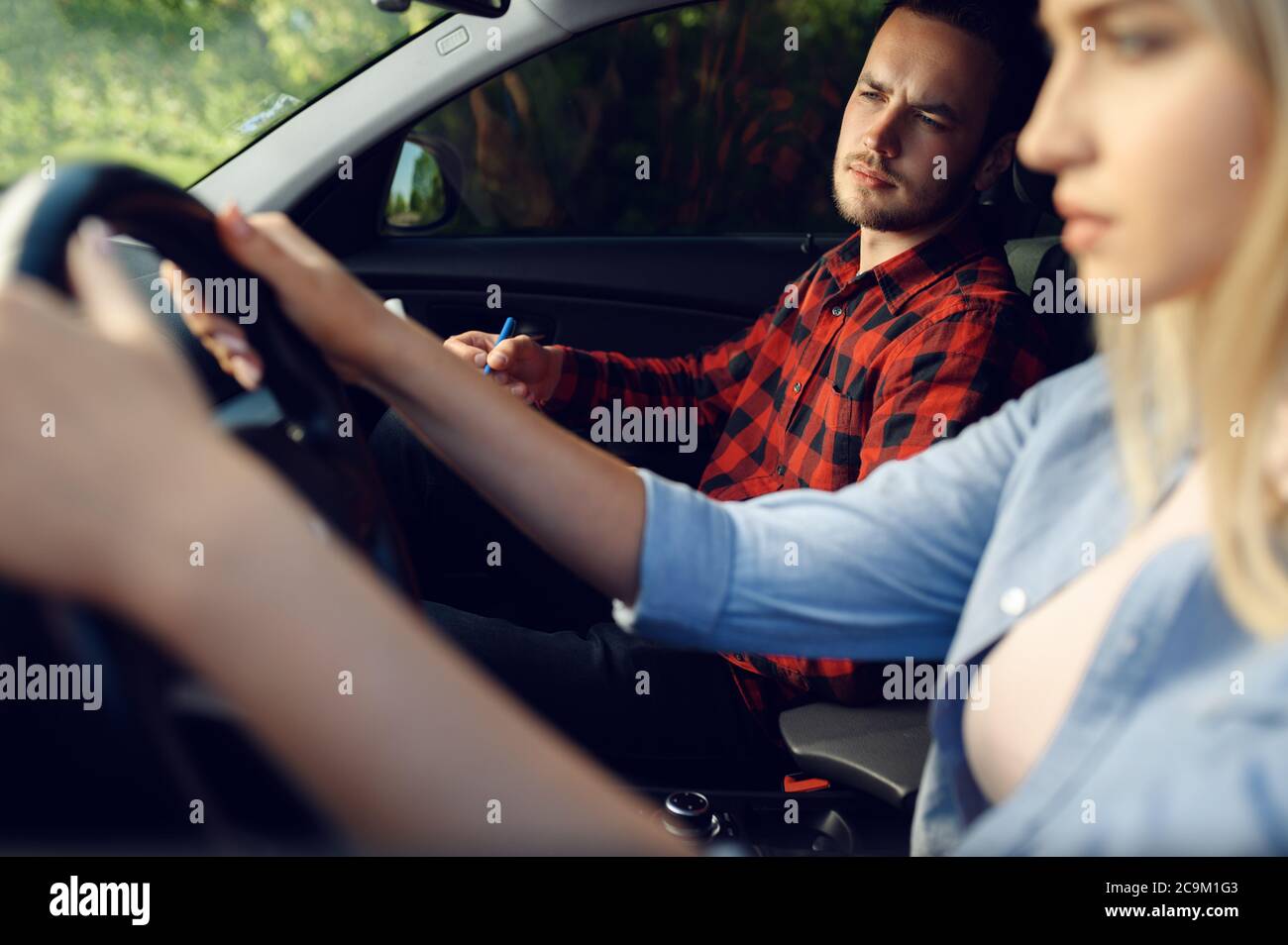 Serious lady and instructor in car, driving school Stock Photo - Alamy