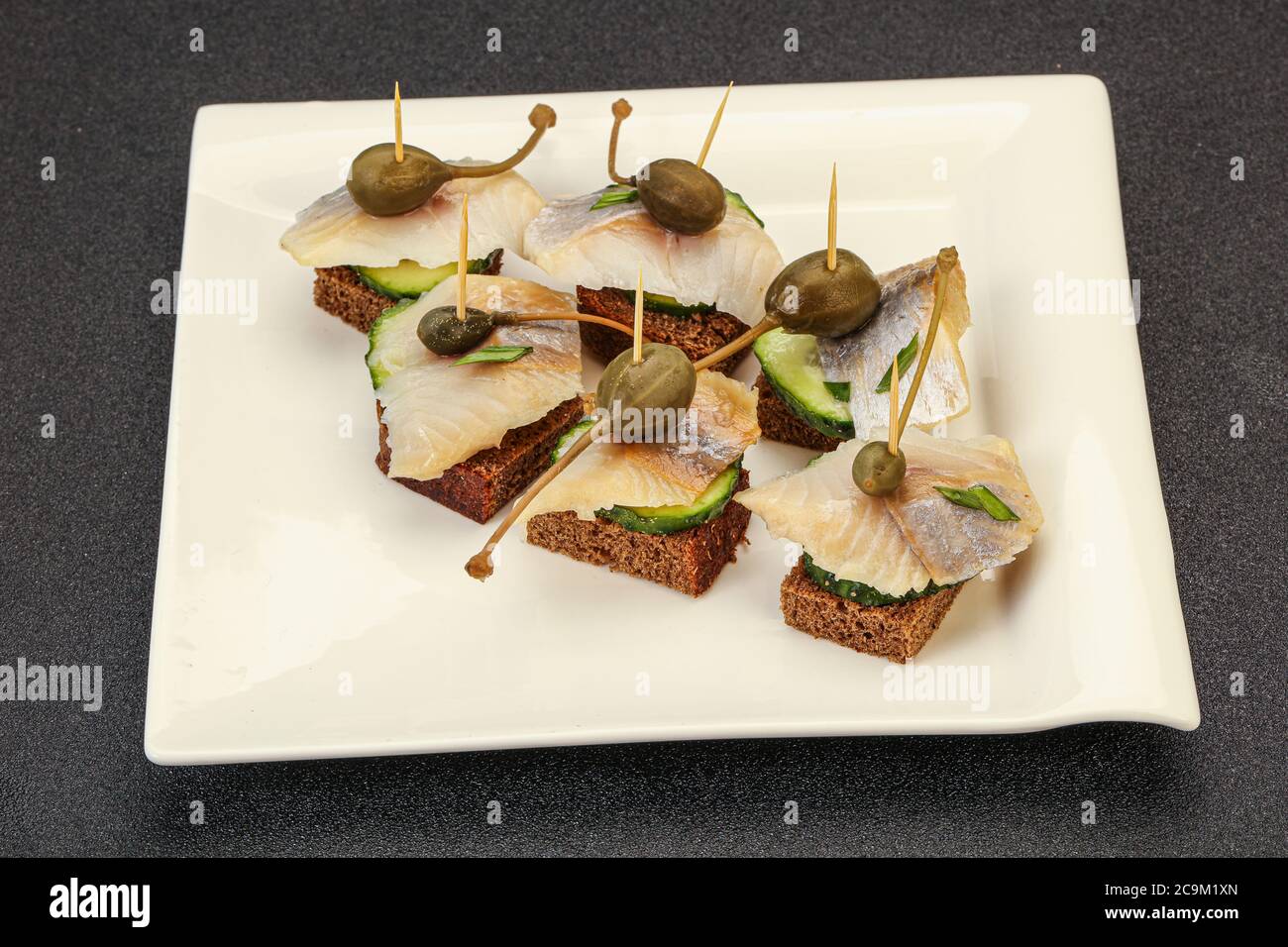 Herring fillet canape snack with caperberry and cucumber Stock Photo ...