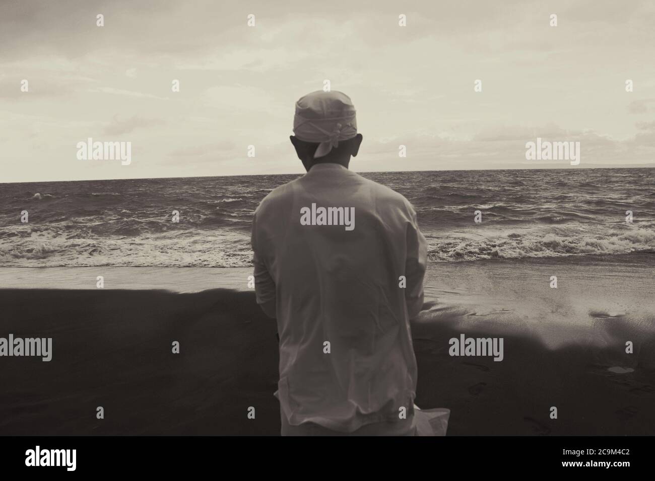 Purifying the spirits: A priest praying as he looks toward the sea ...