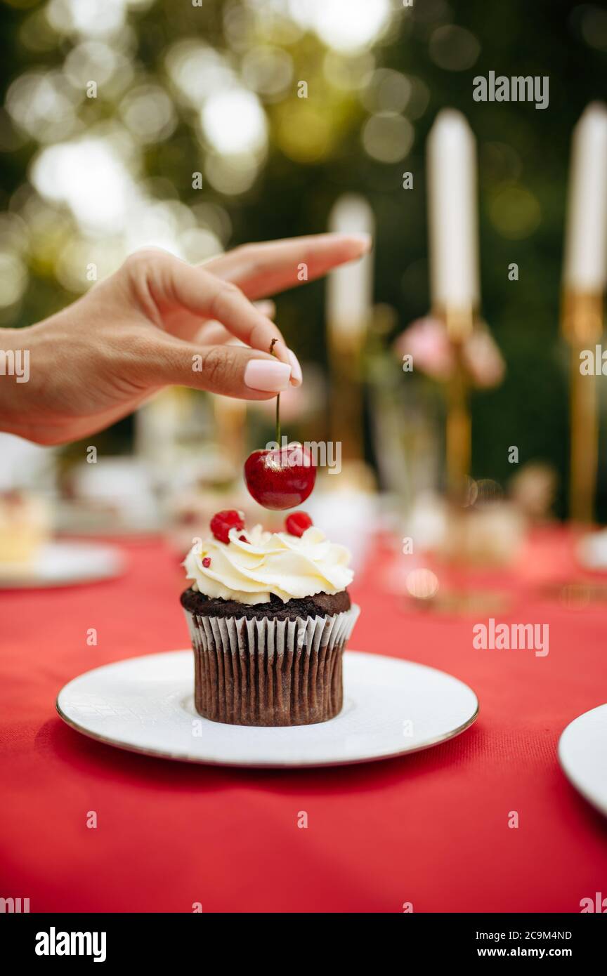Table setting, woman decorate cake with cherry Stock Photo - Alamy
