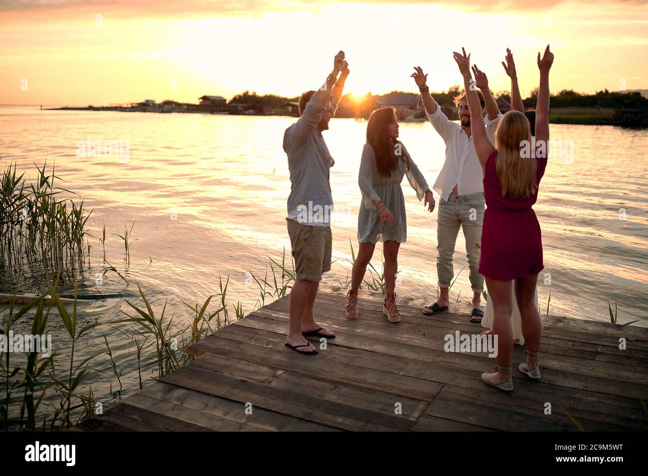 Happy friends having party at the dock on river at evening Stock Photo ...