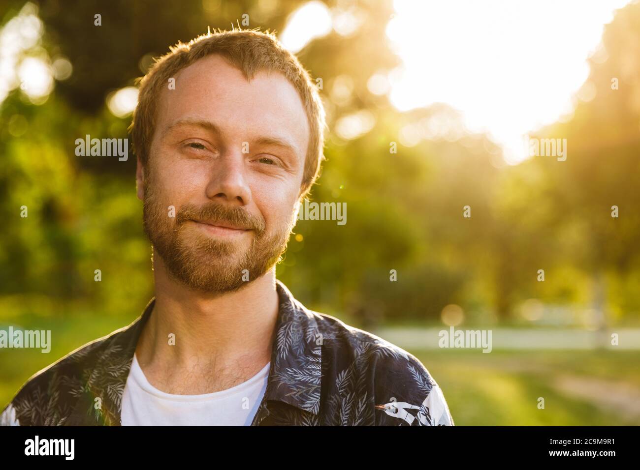 Image of young caucasian bearded man smiling and looking at you while ...