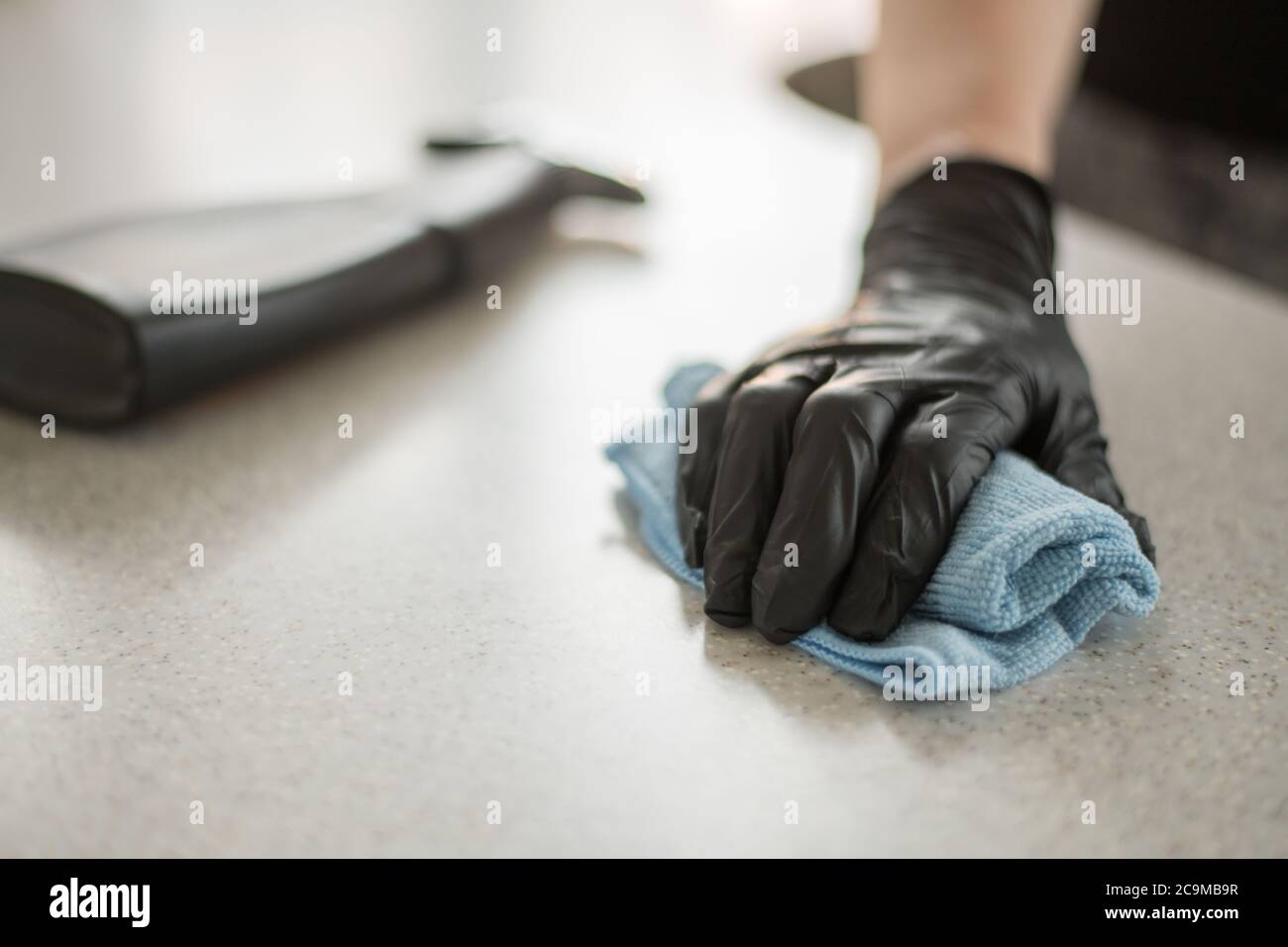 A hand in black gloves holds a microfiber cleaning cloth and a spray ...