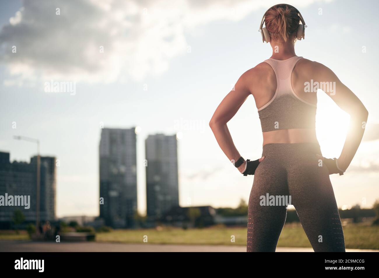Back view of strong fitness woman in sportswear and headphones, back ...