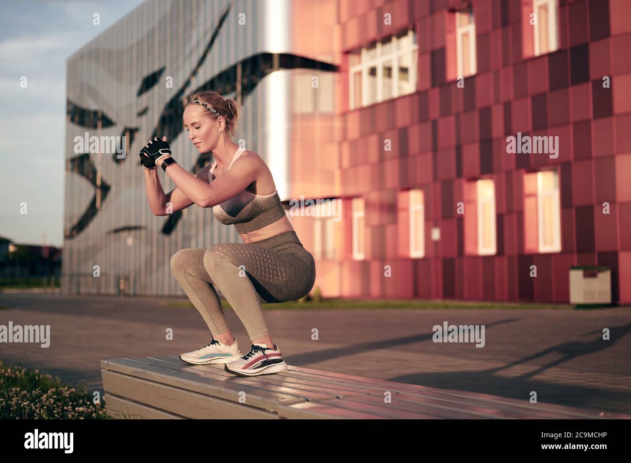 Woman athlete is jumping on bench in park. Sporty girl is doing ...