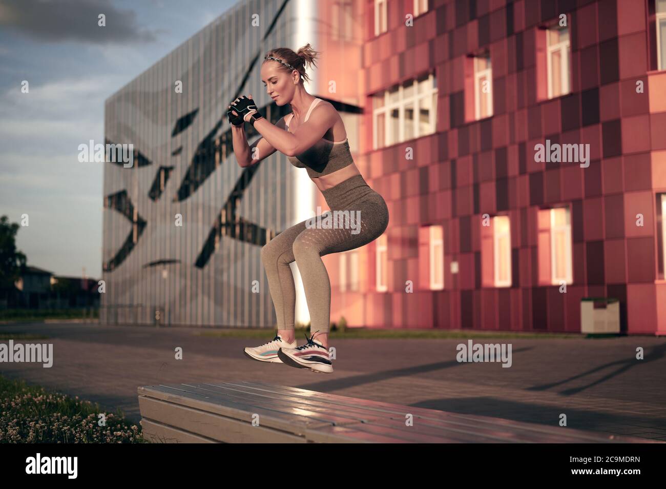 Female athlete doing workout cardio activity and jumping on bench ...