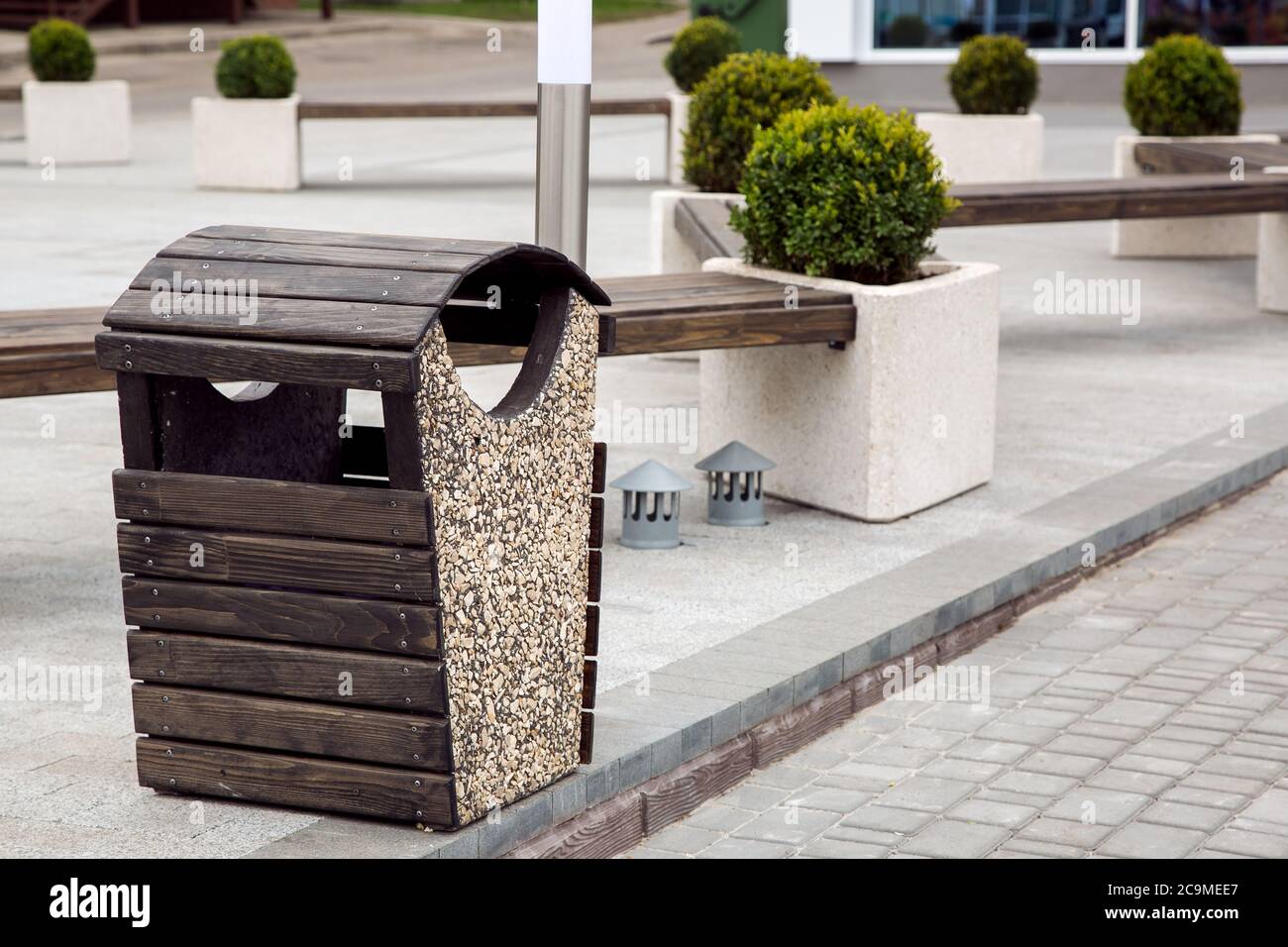 An outdoor garbage bin decorated with stone and wooden planks stands on ...