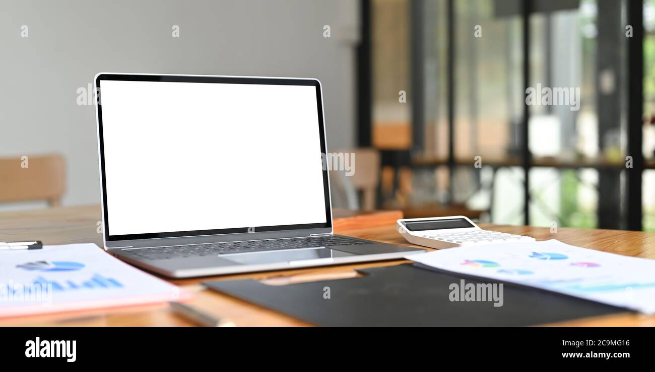 A wooden working desk is surrounding by a white screen computer laptop ...