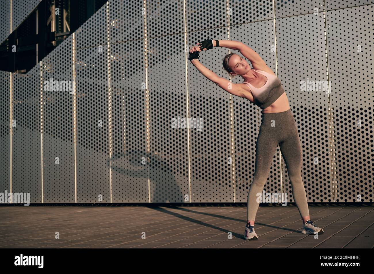 Strong muscular girl in sportswear is doing stretching exercise after ...