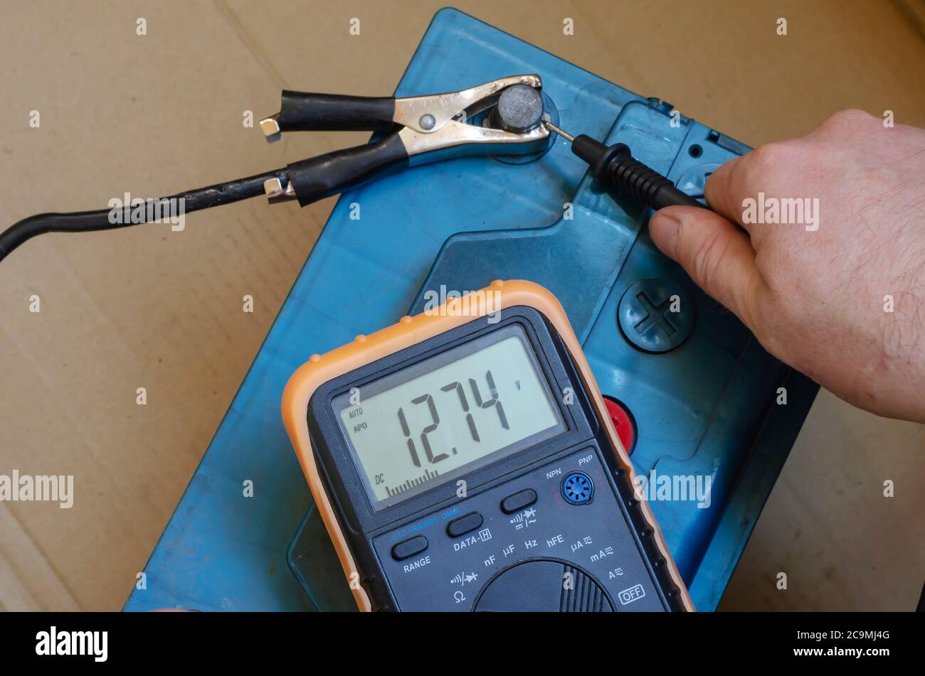Auto electrician checks the charge quality of an auto battery. Takes ...