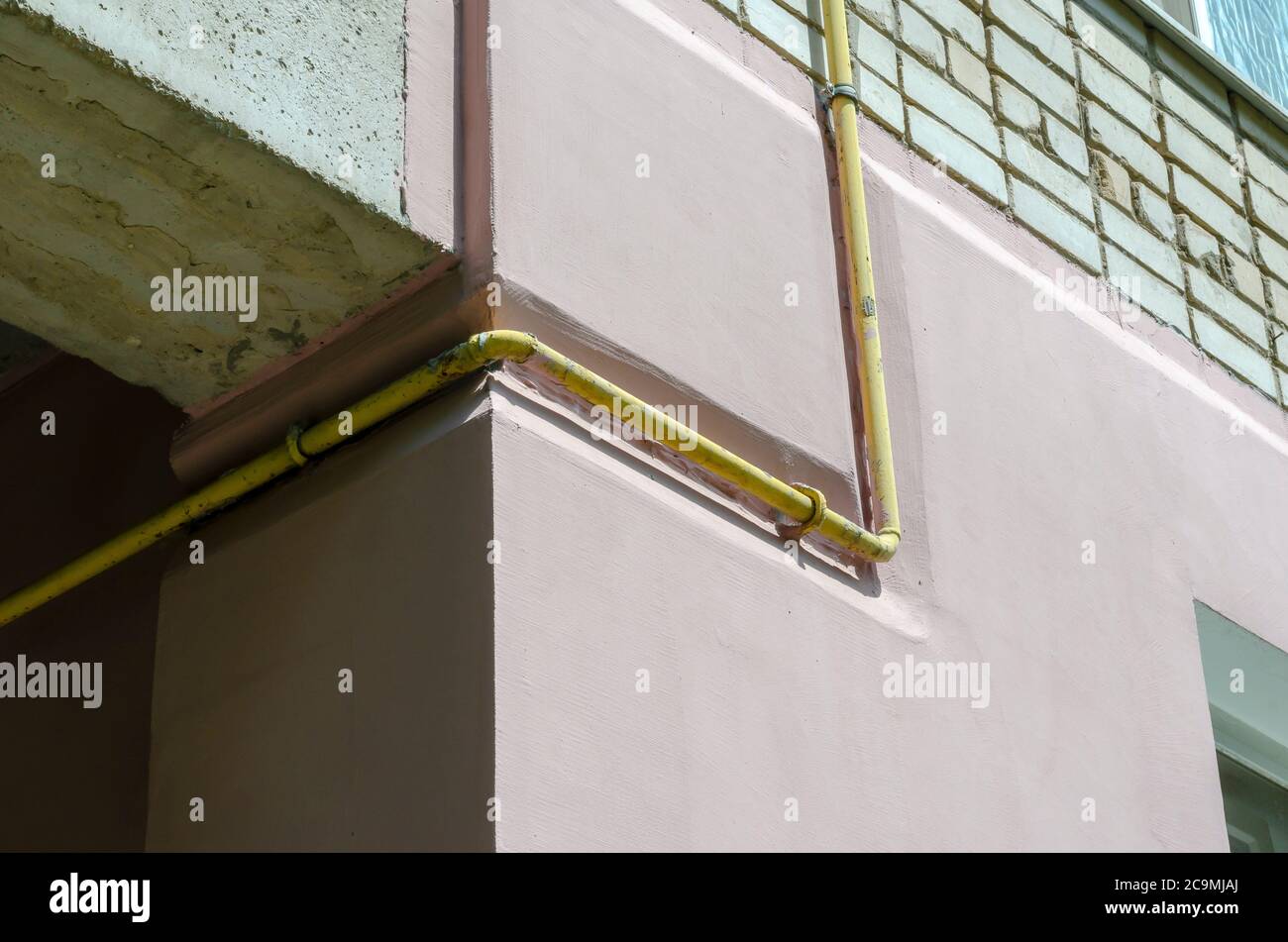 Yellow gas pipe viewed on the outer brick wall of residential building ...