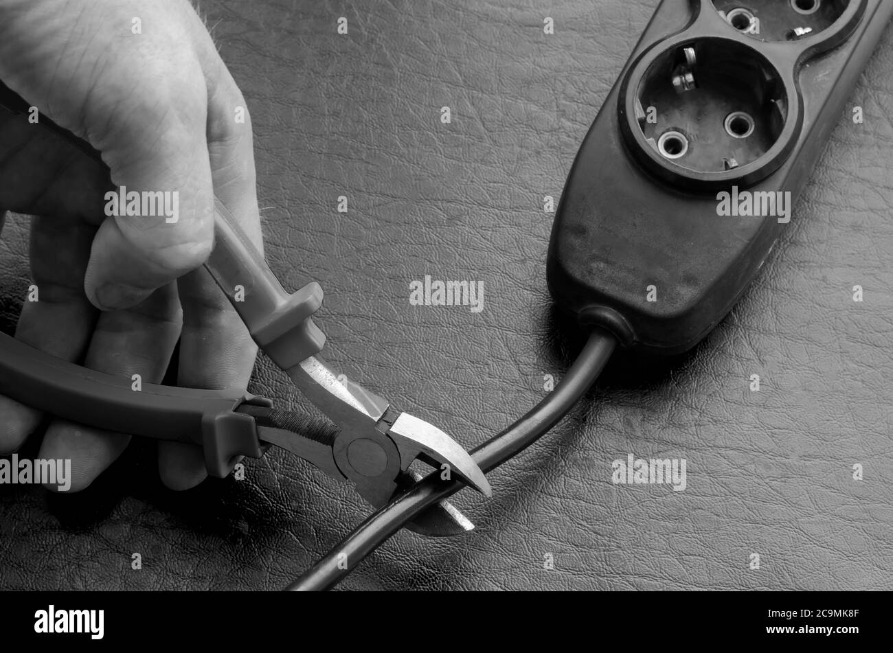Hand of a Caucasian man biting an electric cable with cutters ...