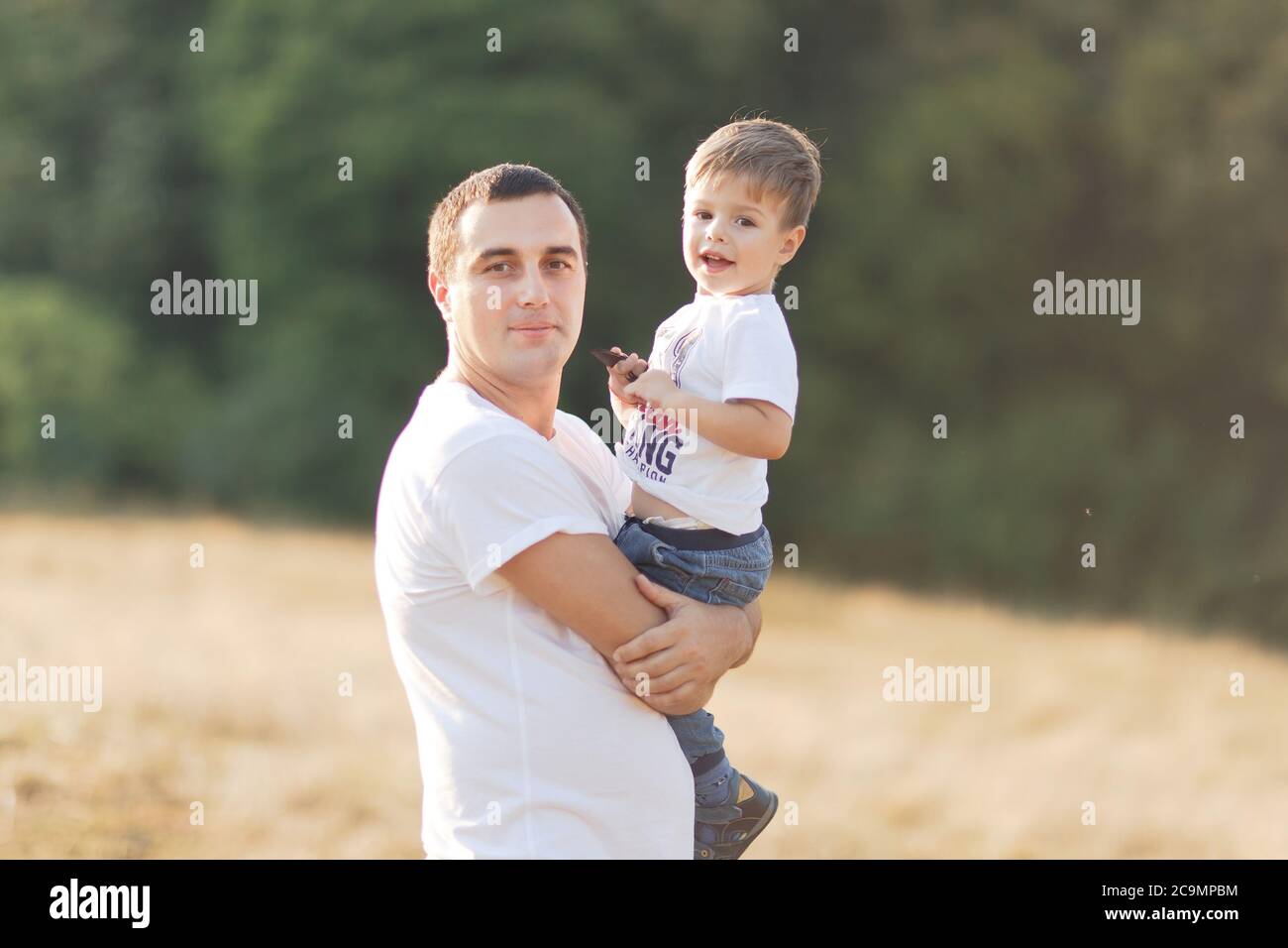 Family with children walking outdoors in summer field at sunset. Father ...
