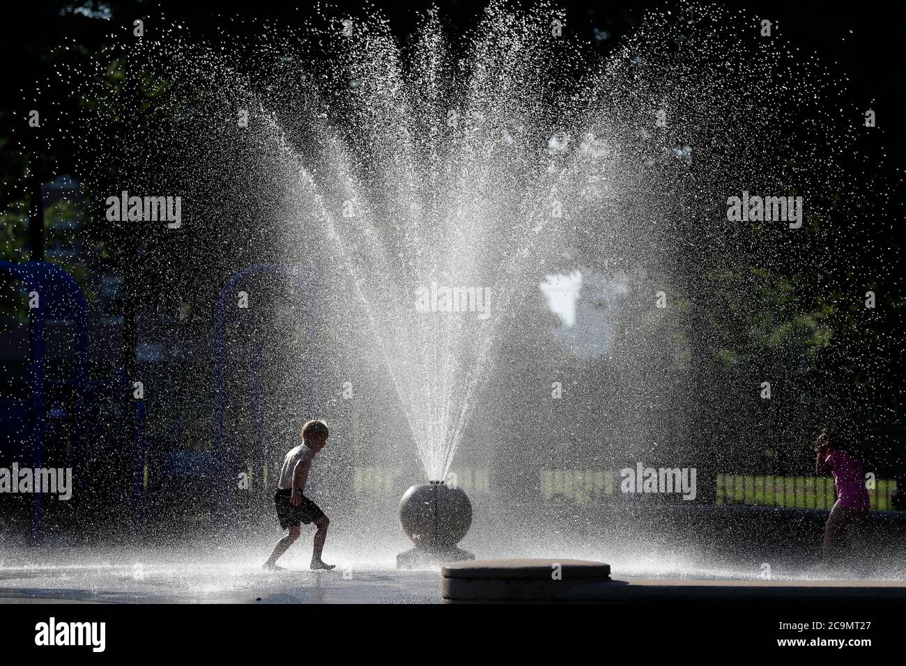 Child playing in backlit water fountain, Piers Park, Boston ...