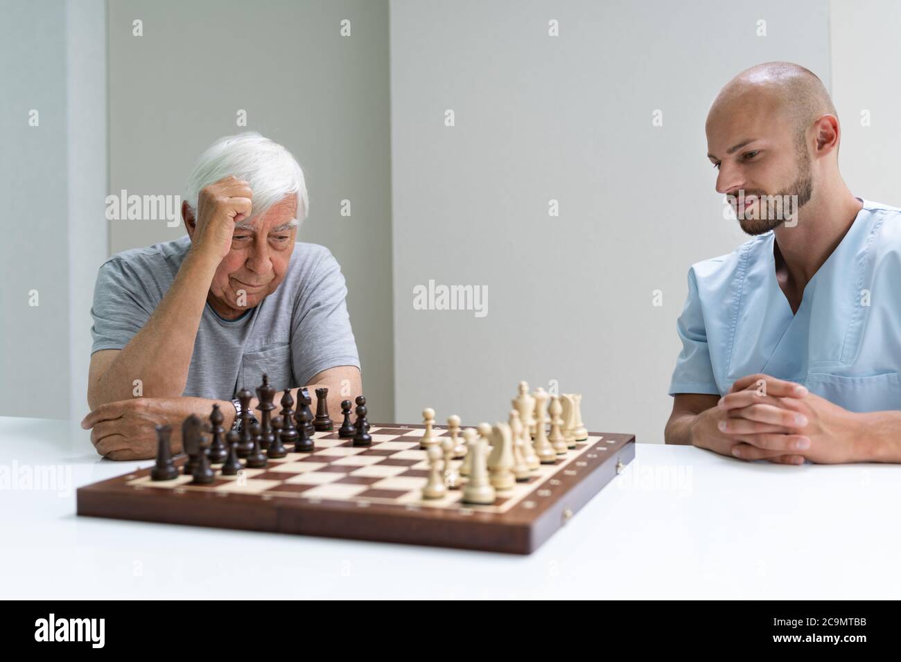 Elderly Senior Playing Chess With Caregiver At Home Stock Photo - Alamy
