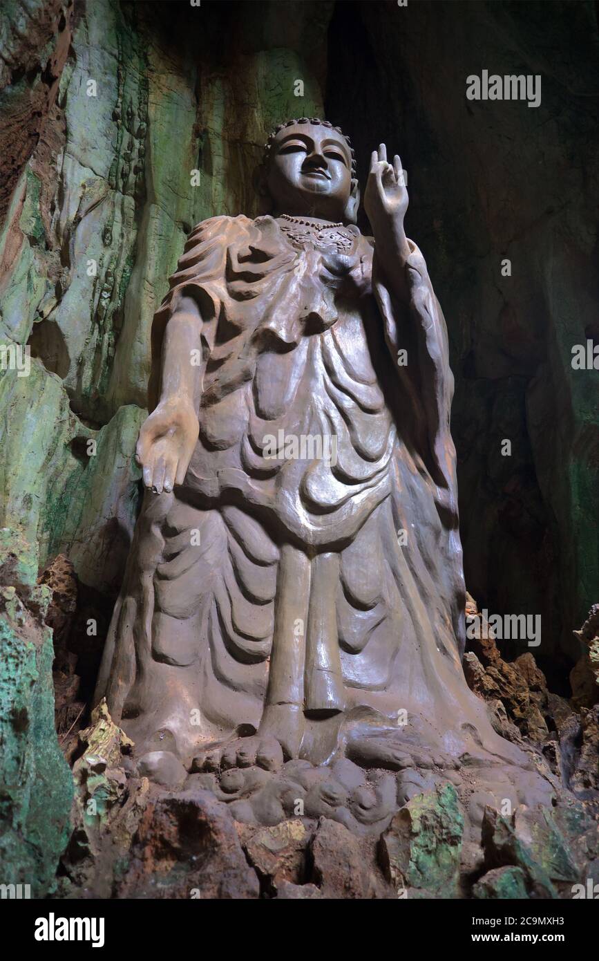 At an ancient sculpture of a standing Buddha. Tang Chon caves in the ...