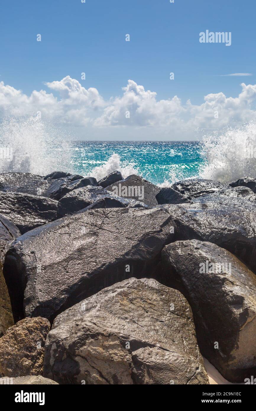 Waves crashing over a rock barrier on a beach, on the island of ...
