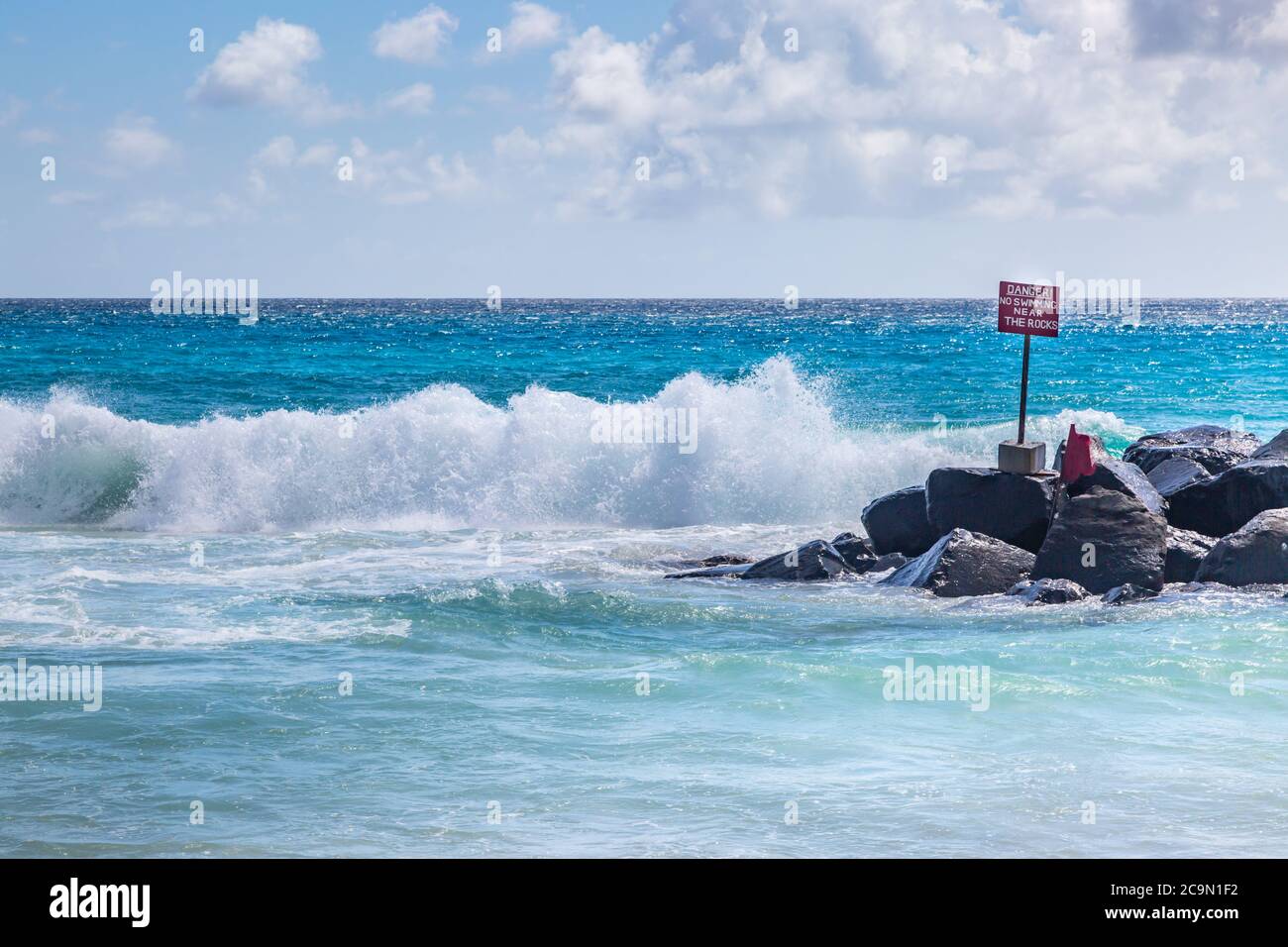 A danger sign near rocks in the ocean, on the Caribbean Island of ...