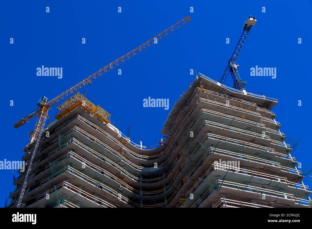 High rise building under construction, seen from below against blue sky ...